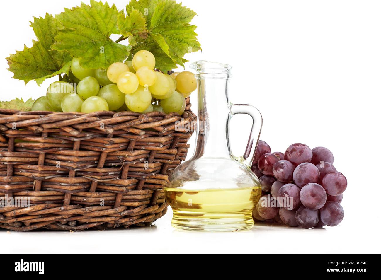 Grape seed oil on white background. The image also shows light grapes ...