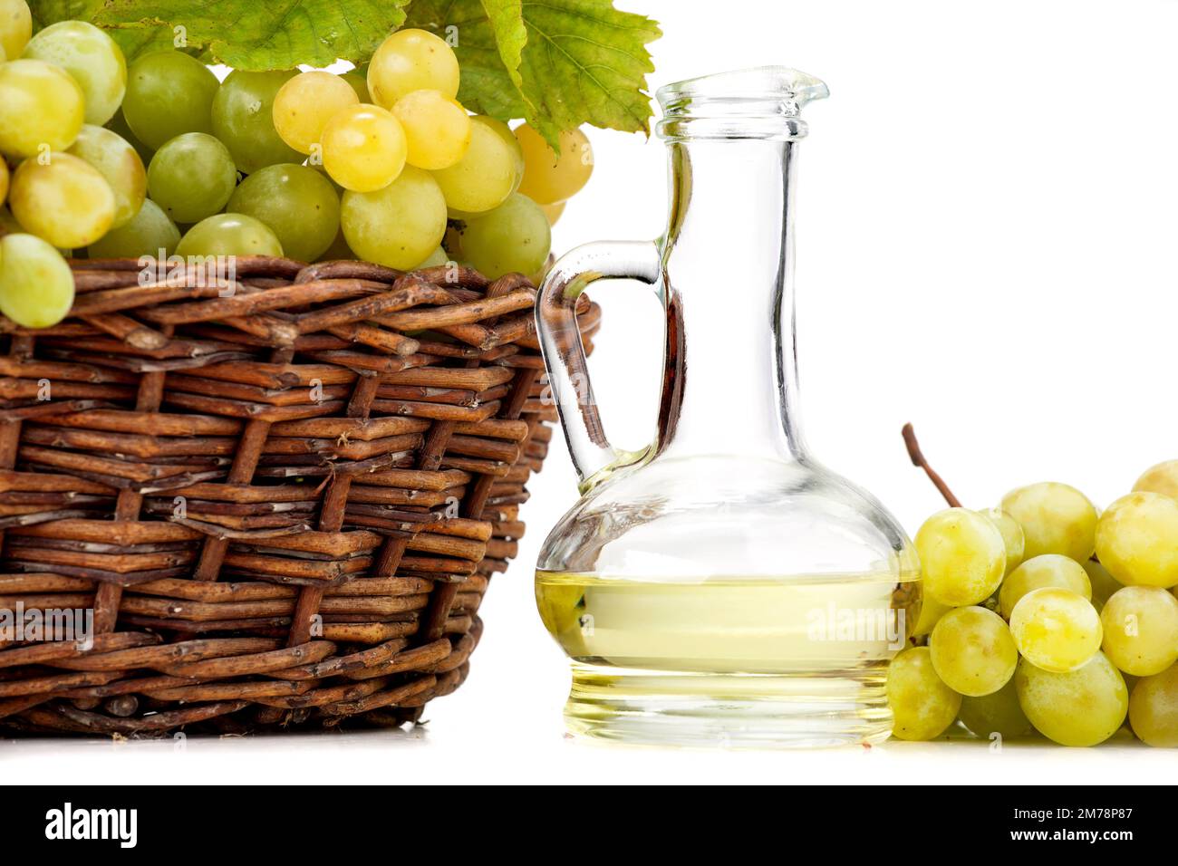 Grape seed oil on white background. The image also shows light grapes ...