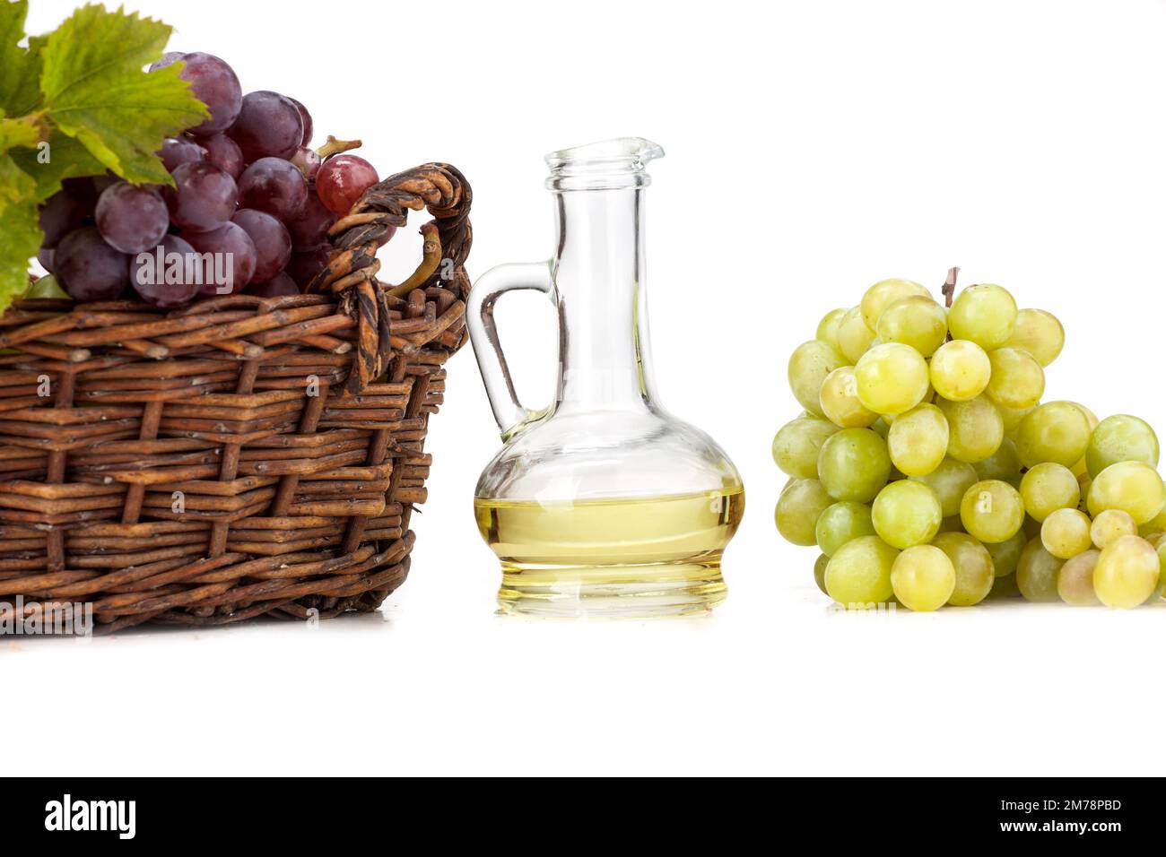 Grape seed oil on white background. The image also shows light grapes ...