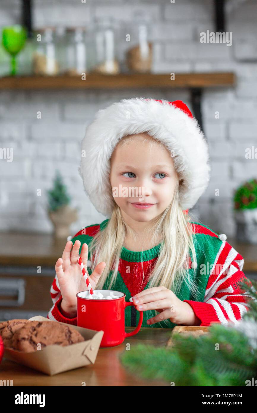 Cute little child girl eating sweet cookies and drinking hot cocoa ...