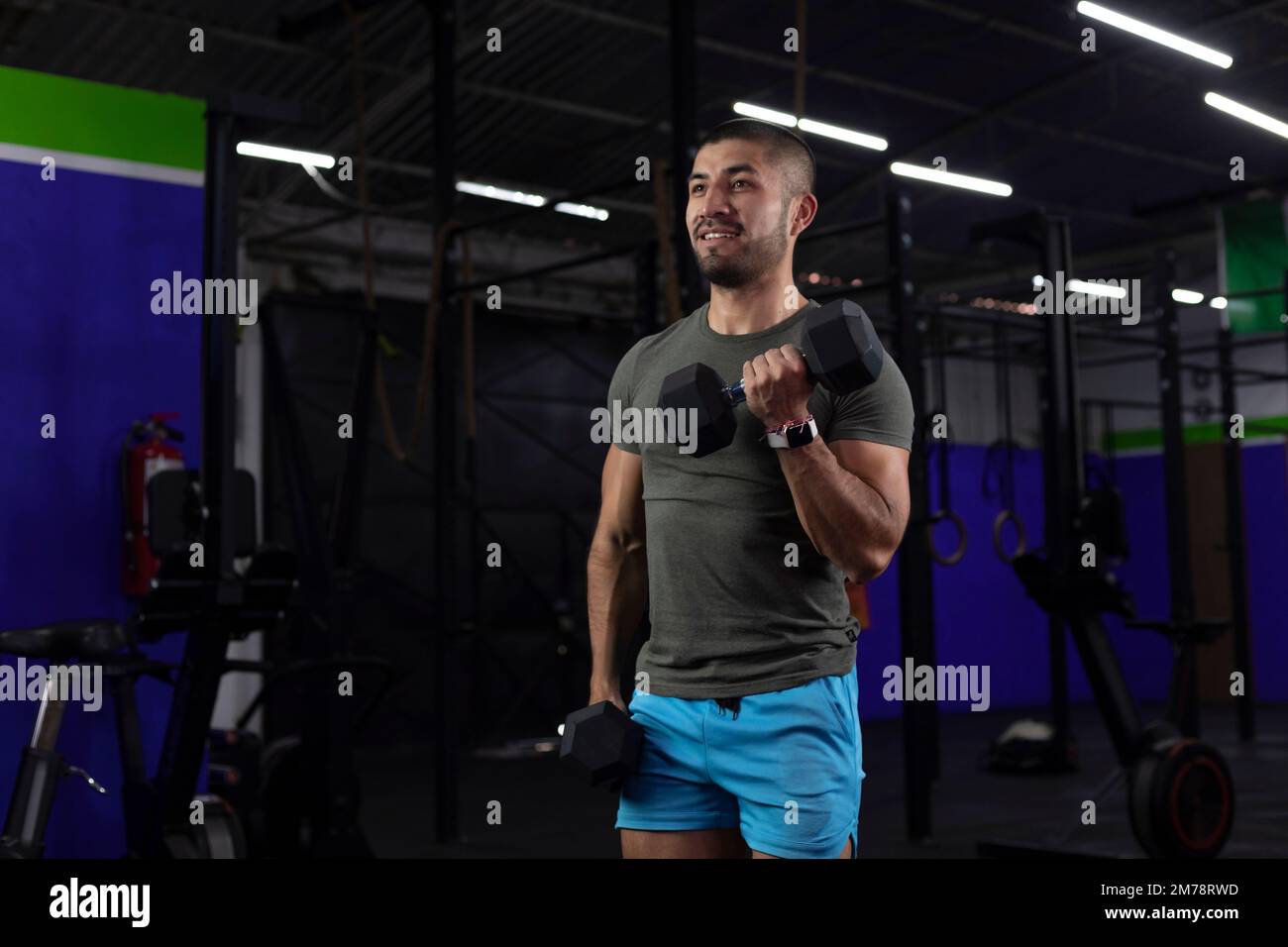 latino man with sportswear doing biceps exercises with two dumbbells in ...