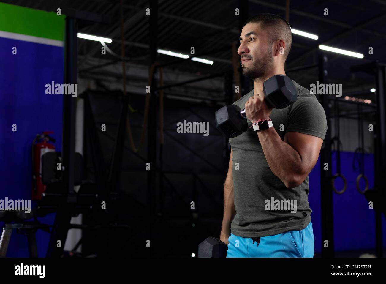 latino man with sportswear doing biceps exercises with two dumbbells in ...