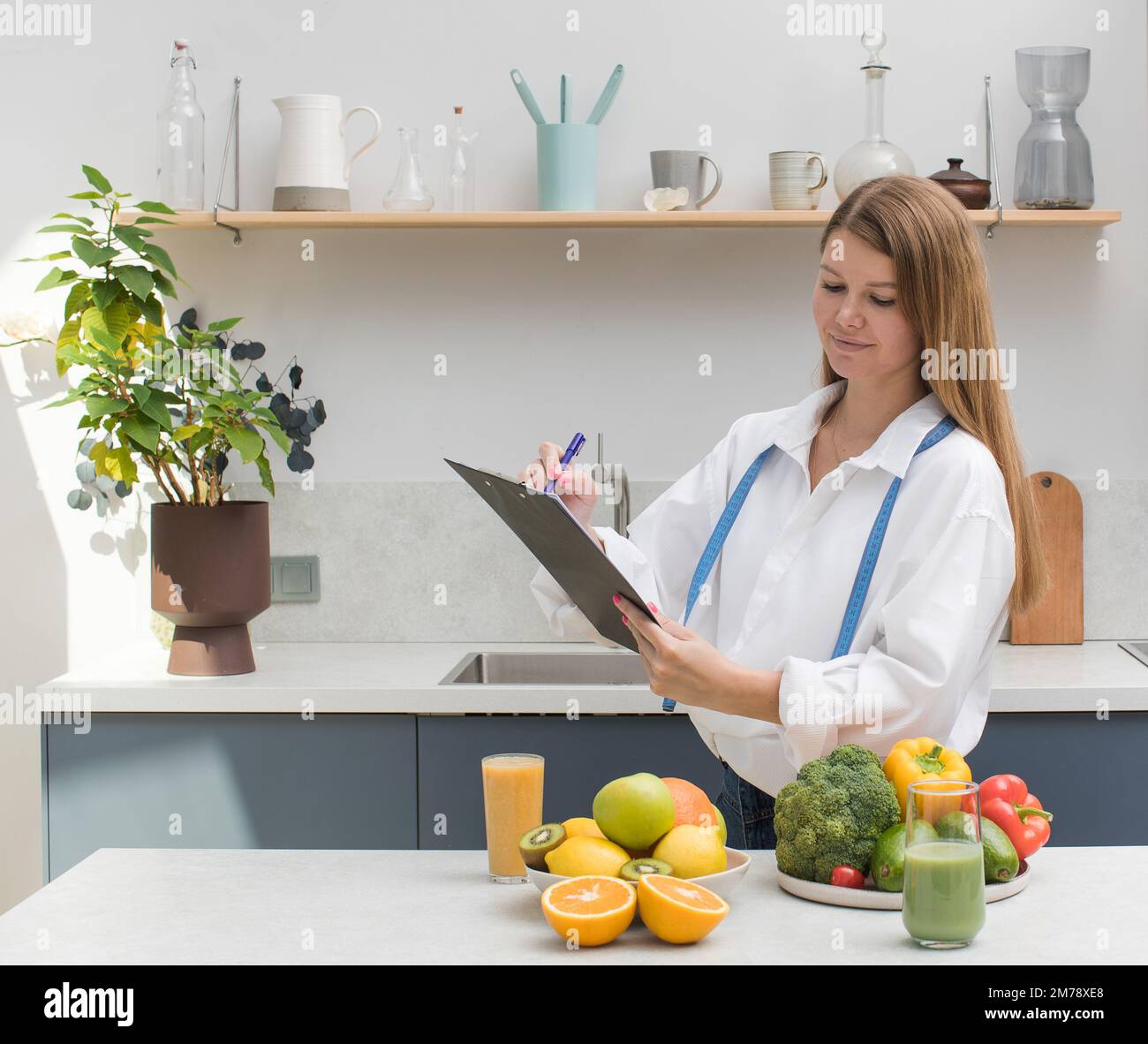 The nutritionist stands at the table with vegetables and fruits and ...