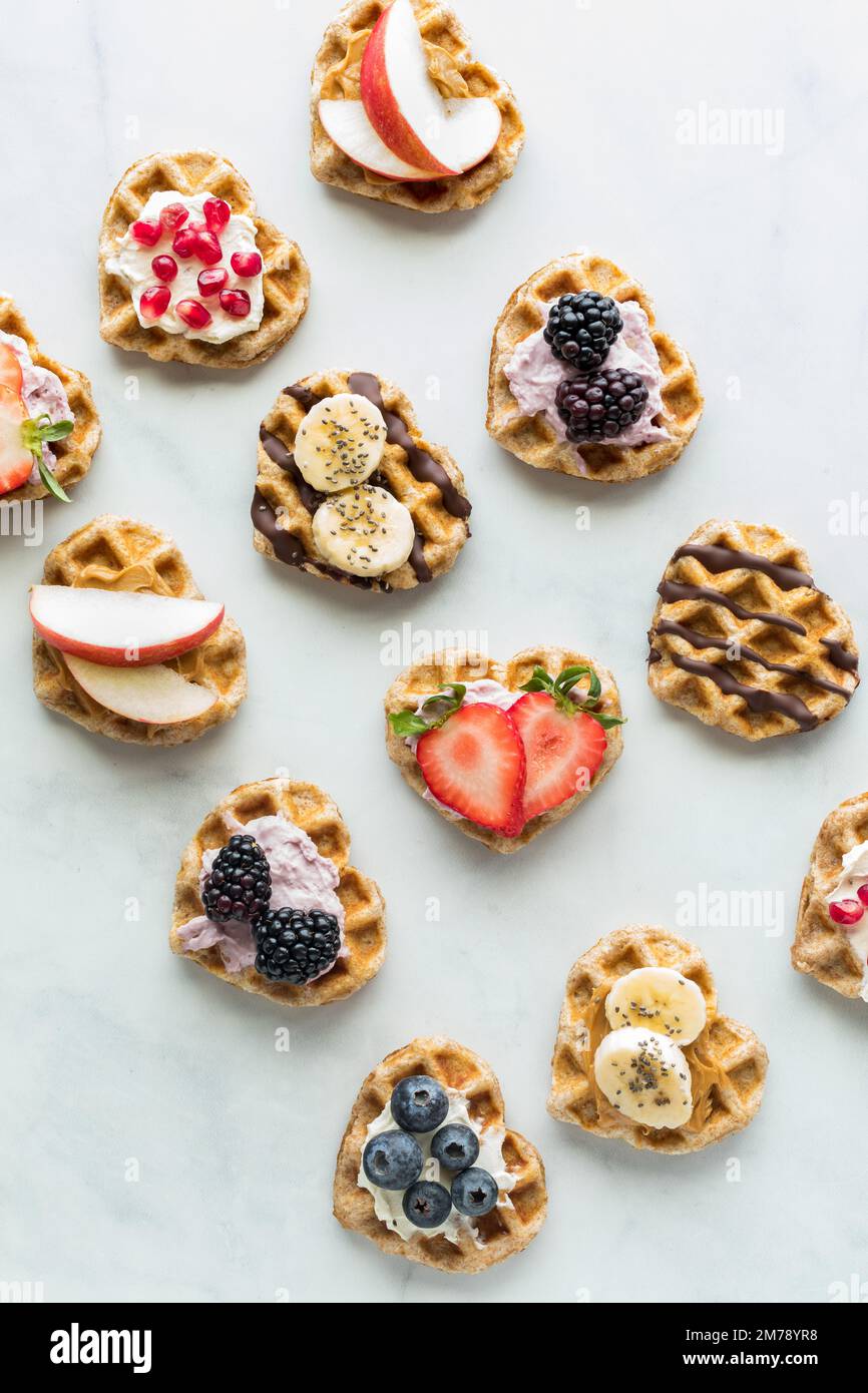 Diagonal rows of mini heart shaped waffles with various toppings Stock ...