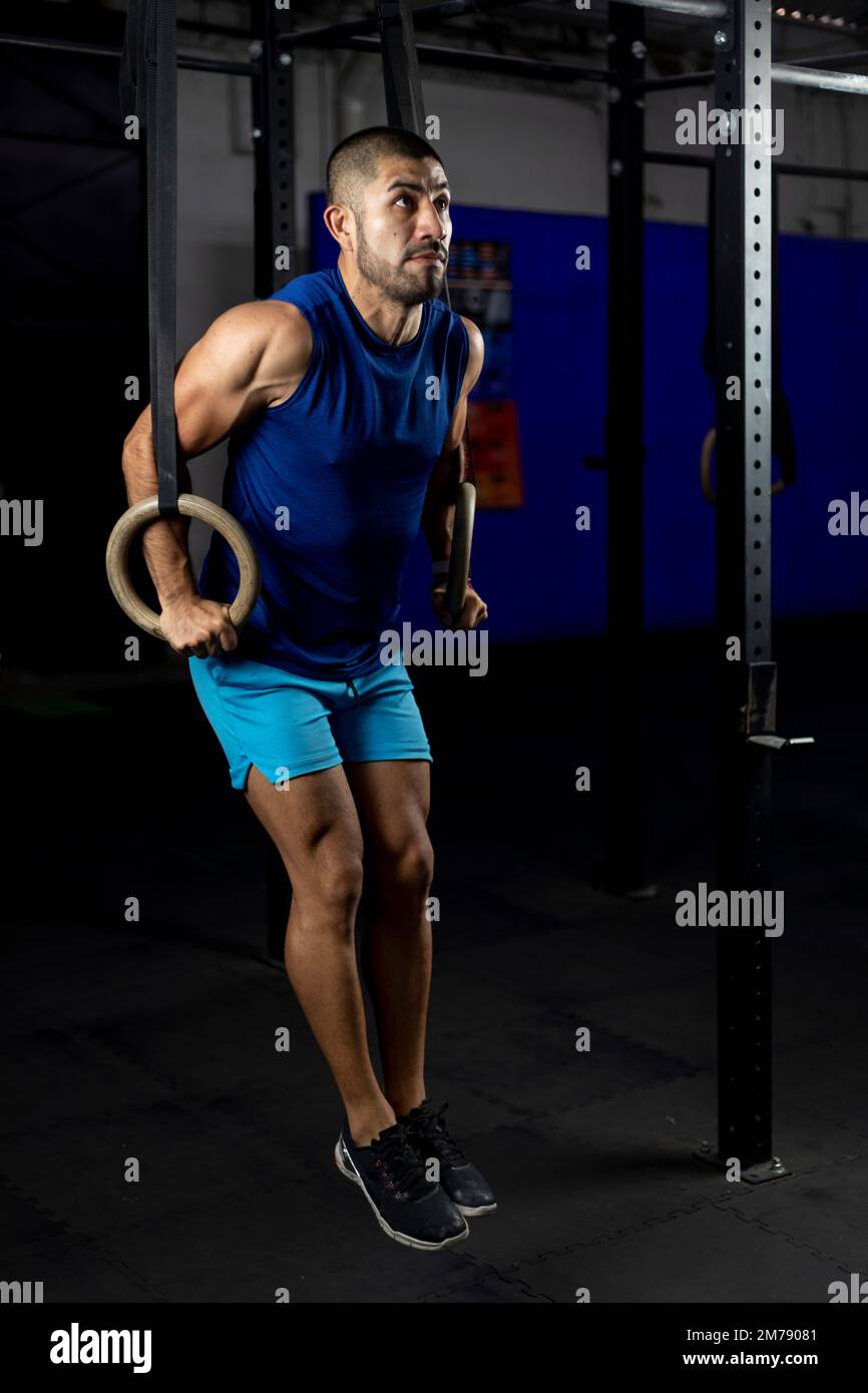 Vertical shot of a gymnast doing ring dips in the haros of a gym Stock ...