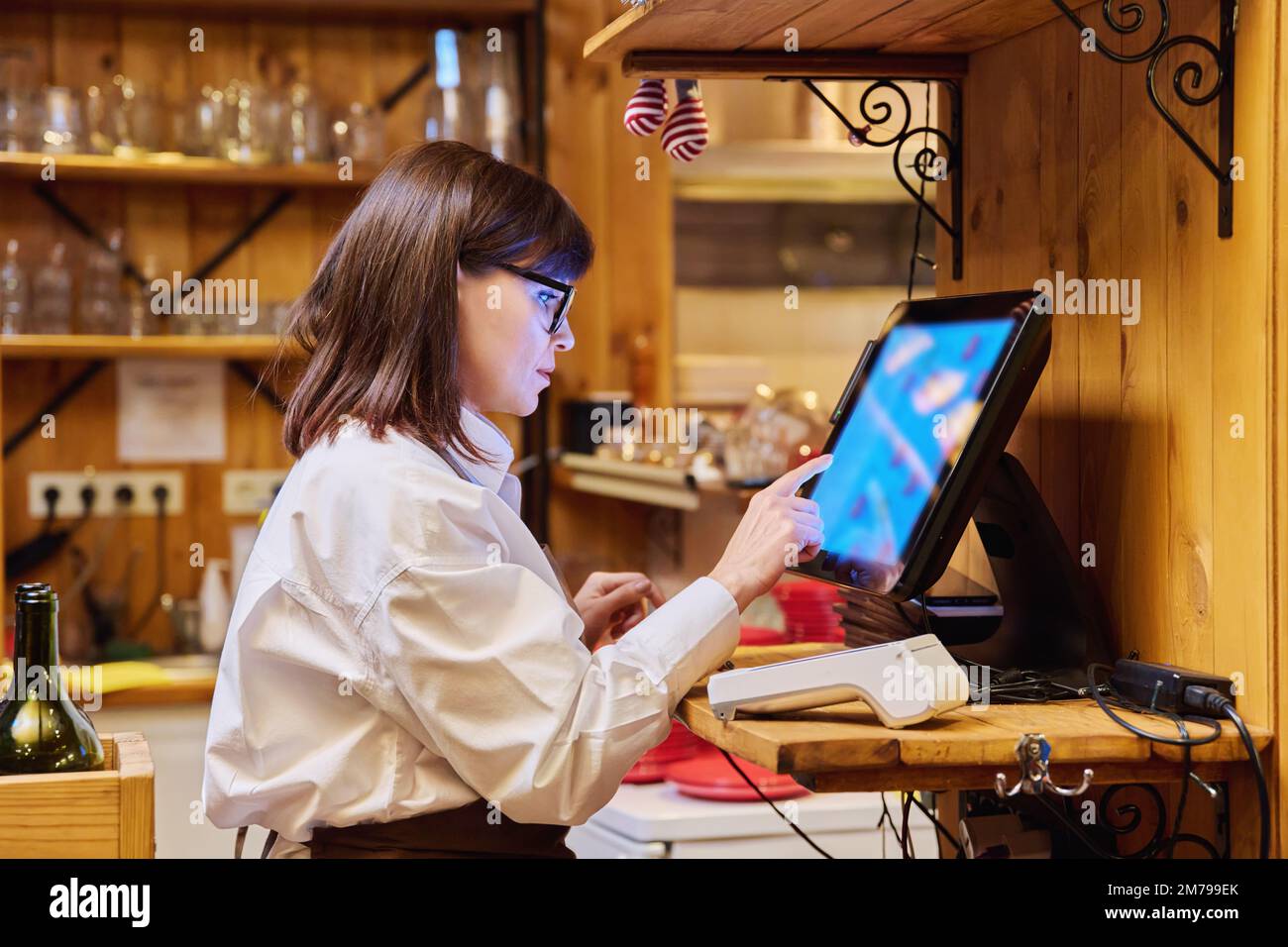 Female restaurant worker using computer terminal while serving ...