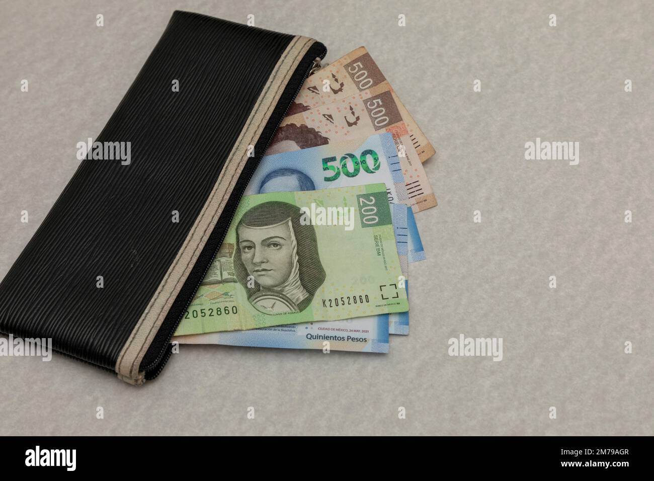 Wallet with Mexican pesos bills of different denominations on a table ...