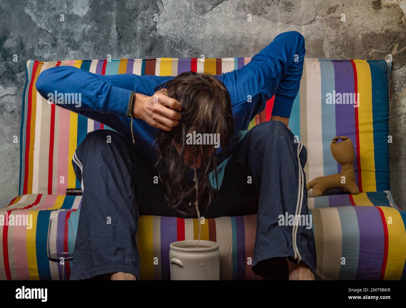 Man vomiting after drinking of alcohol on color sofa with old stone ...