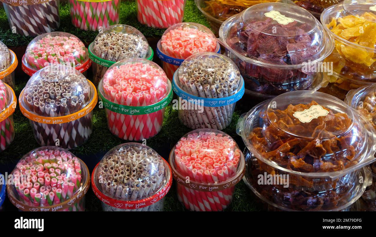 Colorful wafer rolls packed in transparent containers, displayed neatly ...