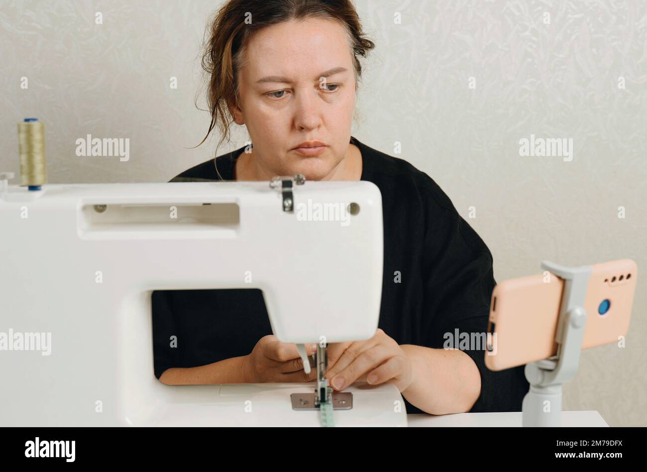Work at home. small business. A female seamstress sews green fabric ...