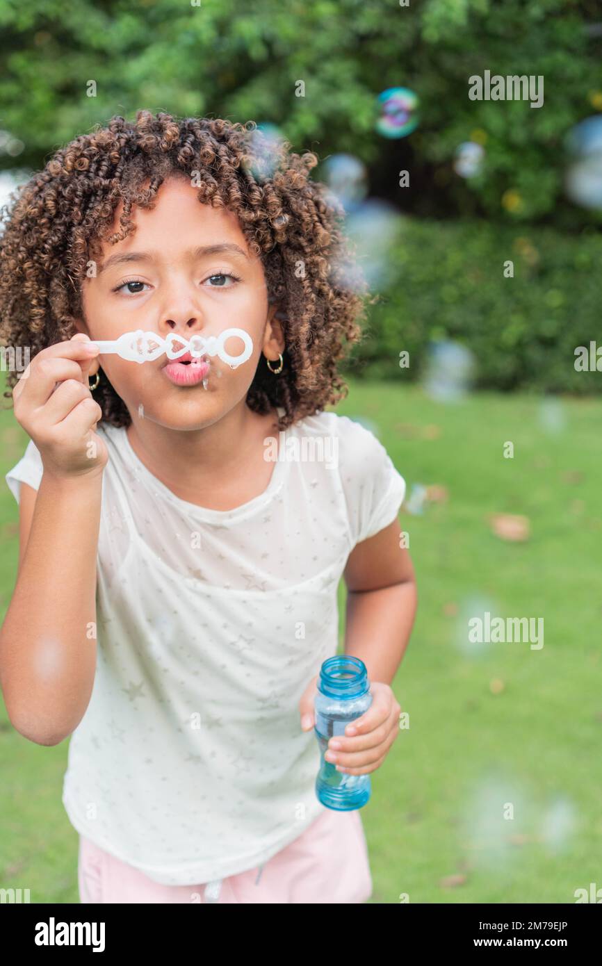 Little girl blowing bubbles in field Stock Photo - Alamy