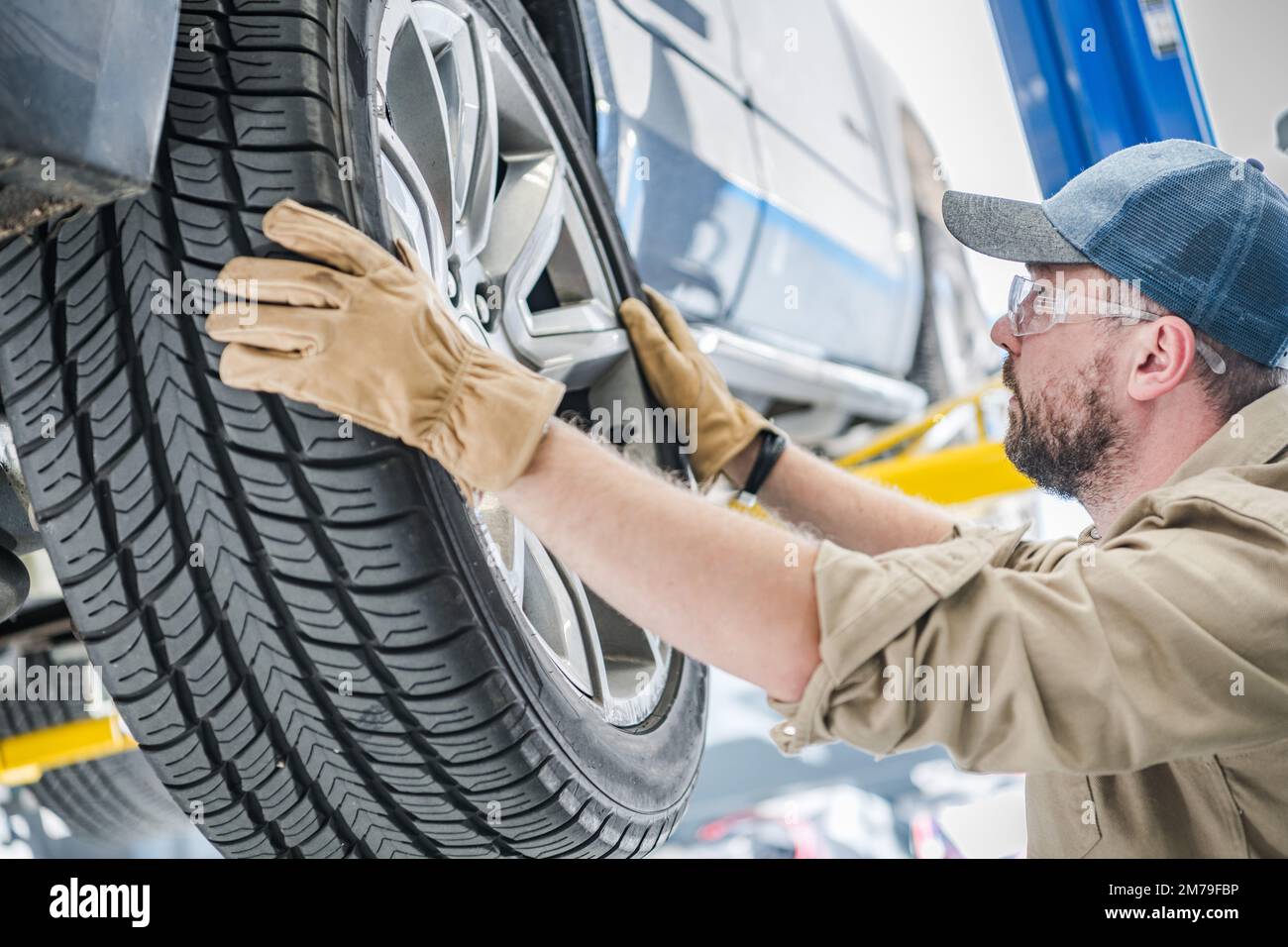 Professional Mechanic Preparing to Remove the Rear Wheel From the Car ...