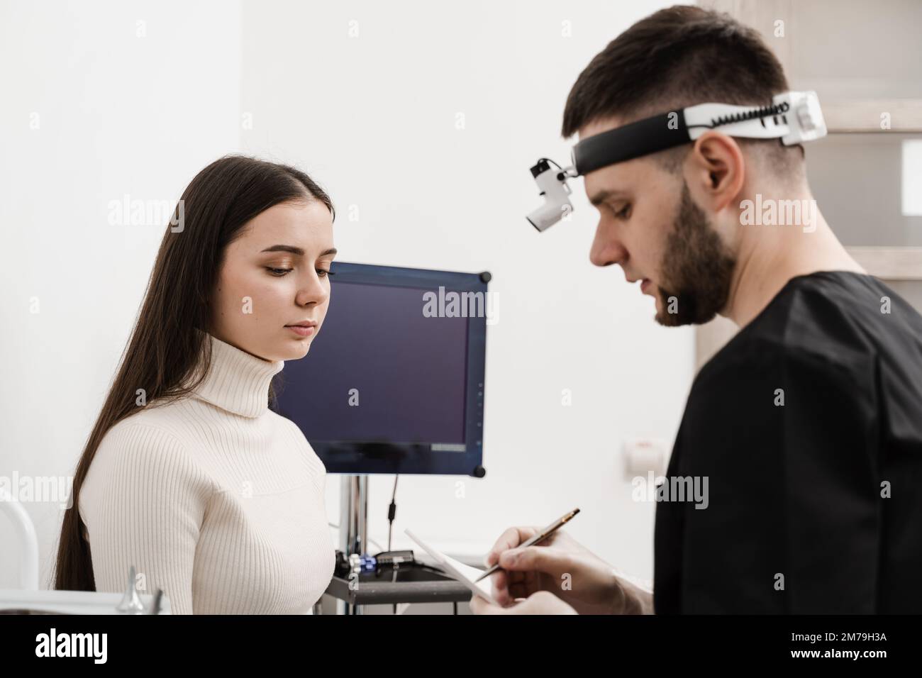 ENT doctor consulting patient and write notes causes of difficulty ...