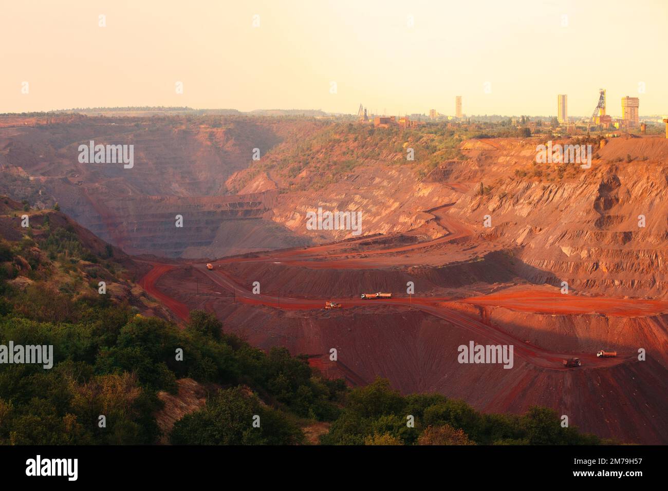 Bulldozers and trucks in quarry with red ground. Mining iron ore in ...