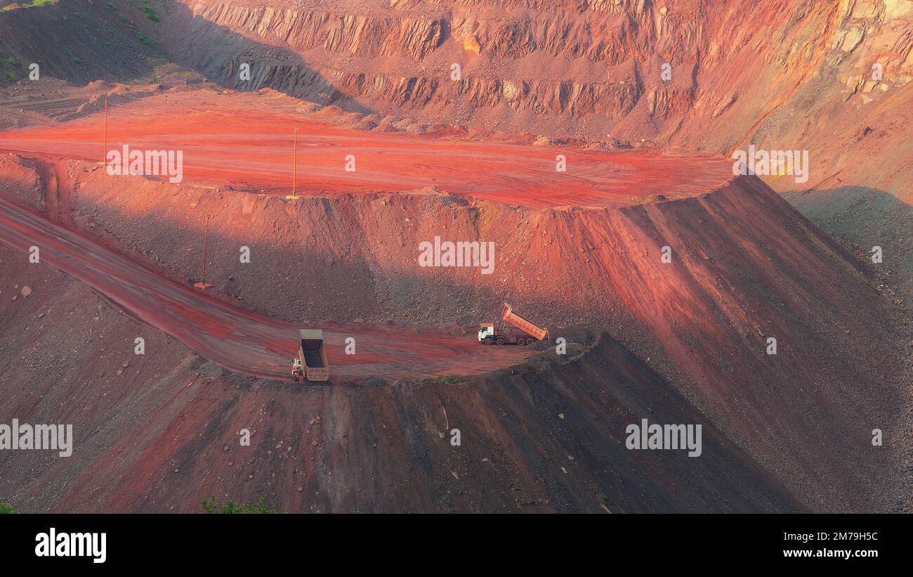 Bulldozers and trucks in quarry with red ground. Mining iron ore in ...