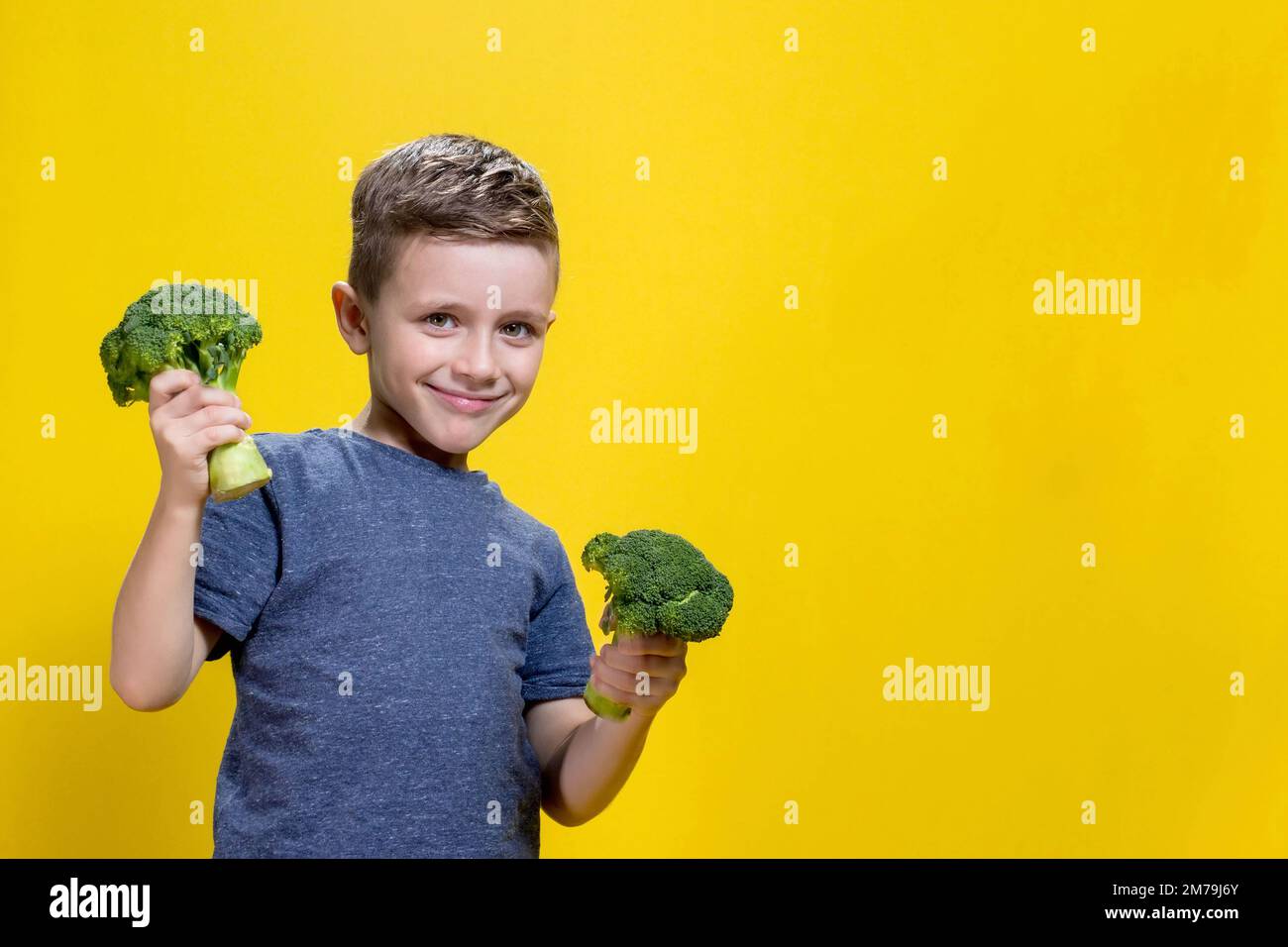 Healthy food, green vegetables broccoli in the hands of a cheerful boy ...