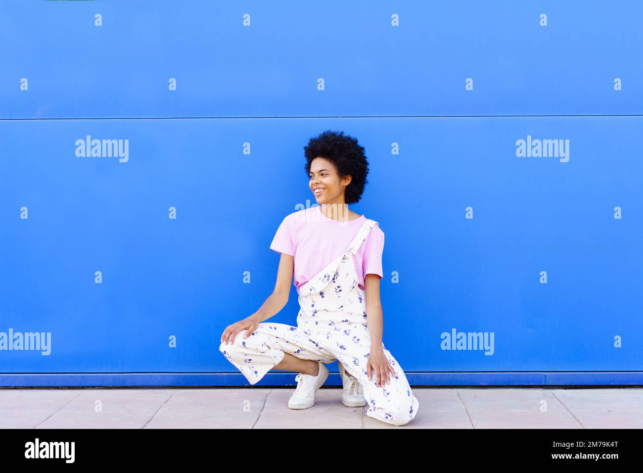 Content black woman hunkering down near wall Stock Photo - Alamy