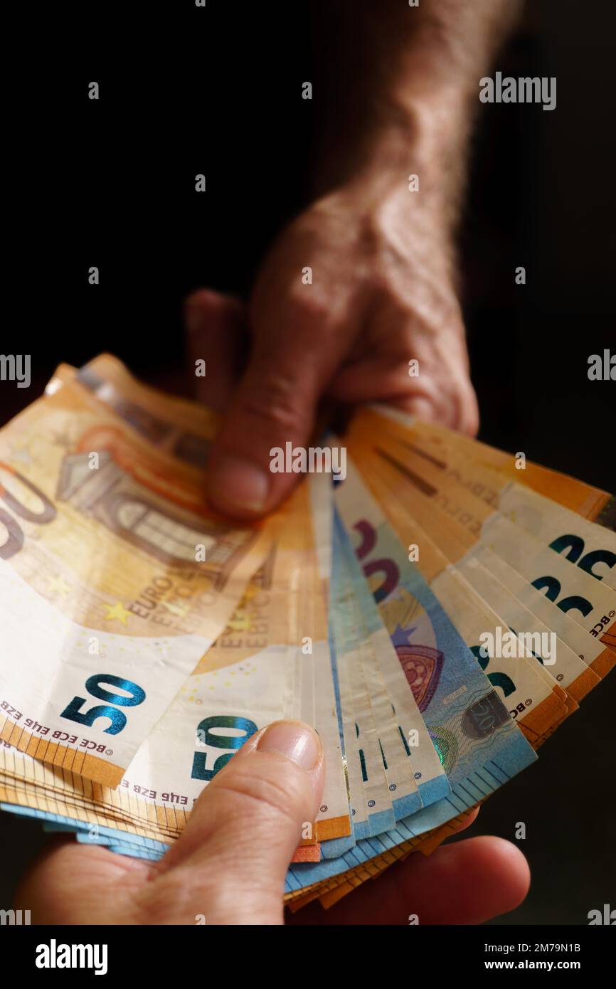 Man's hands handing euro banknotes to woman's hands with black ...