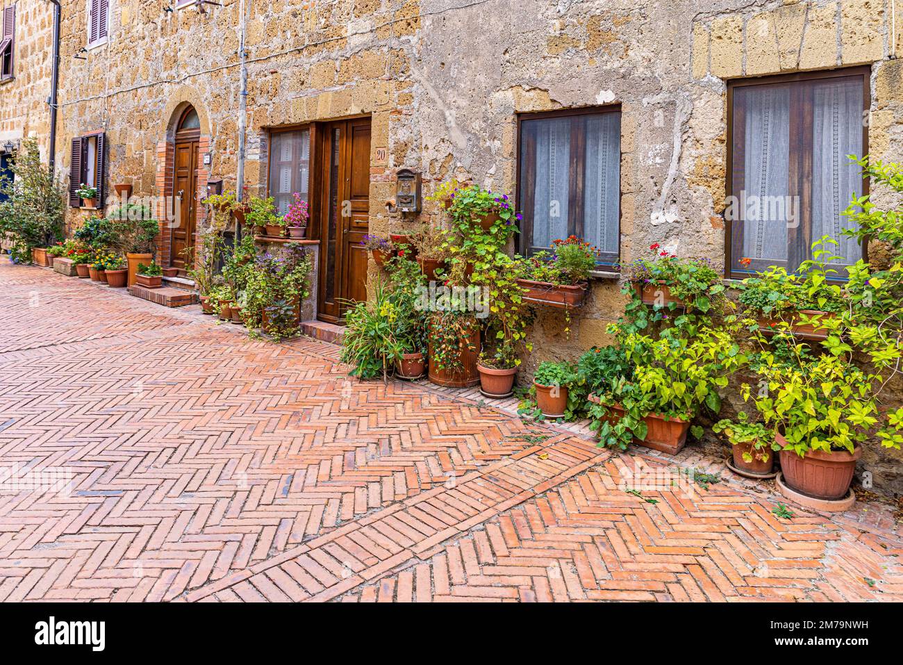 Old stone houses decorated with flower pots, diagonally laid brick ...