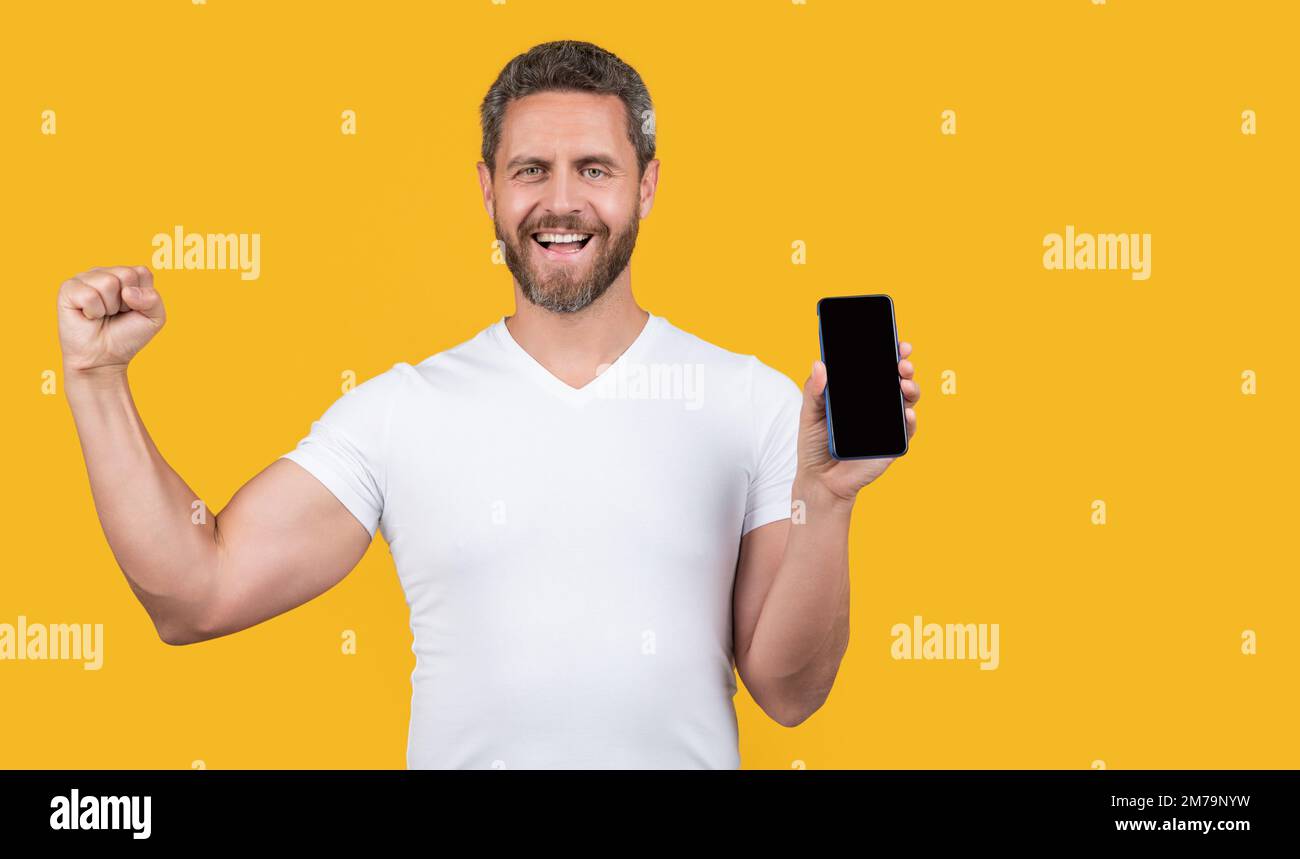 happy man showing phone screen in studio. man showing screen of phone ...
