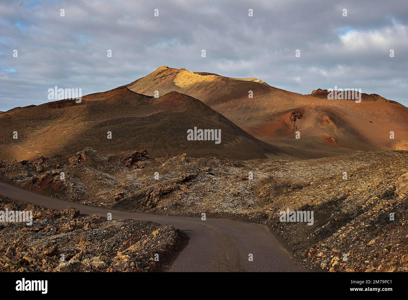 Multicoloured volcanic hill, asphalt road, Timanfaya National Park ...