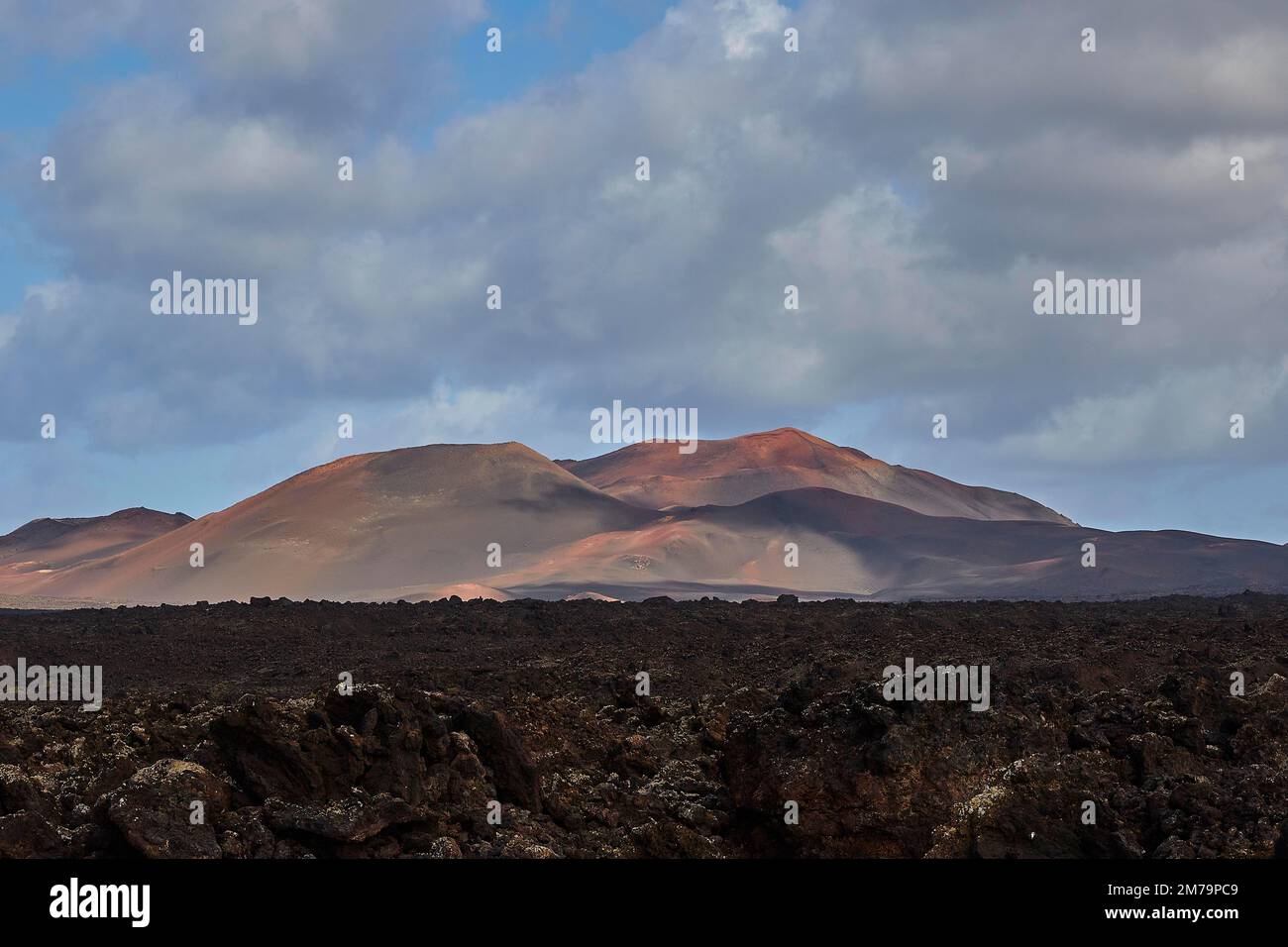 Multicoloured lava mountains, play of light and shadow, dark lava field ...