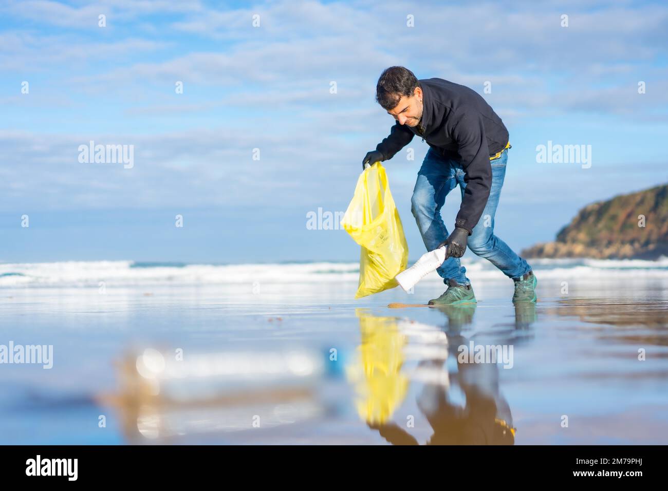 Volunteer man collecting garbage or plastic on the beach. Ecology ...