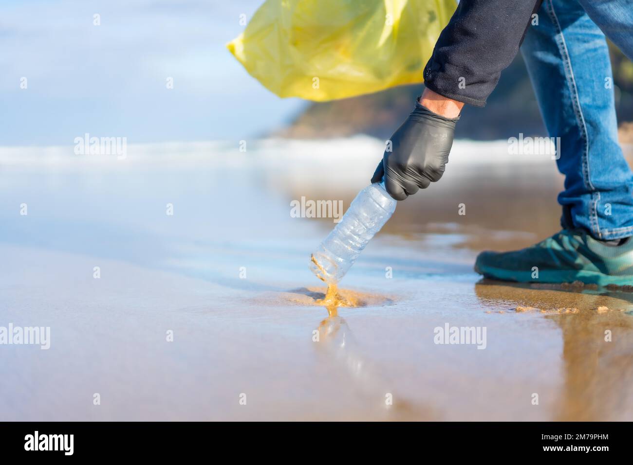 Unrecognizable person collecting garbage or plastic on the beach ...