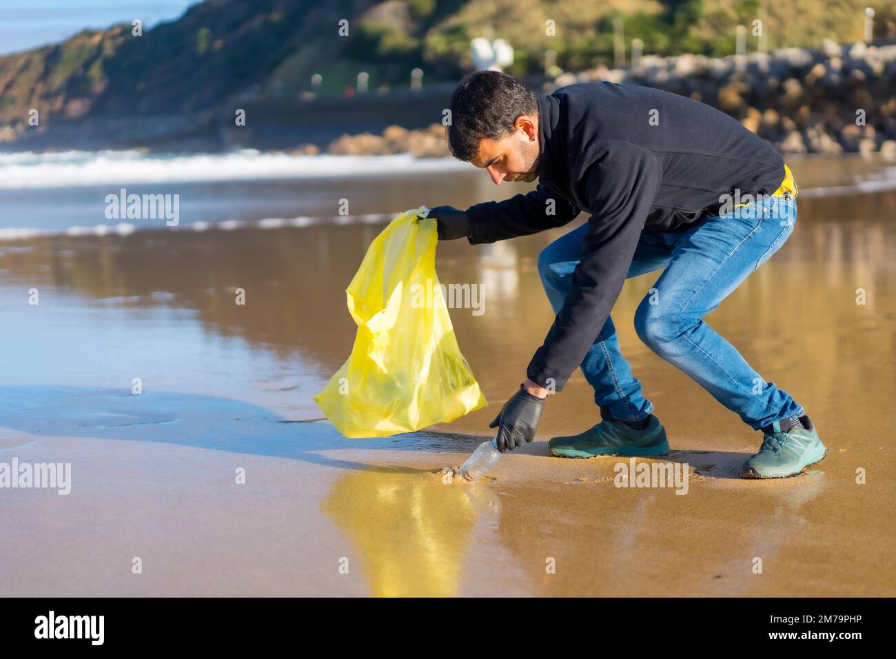 Volunteer man collecting garbage or plastic on the beach. ecology ...