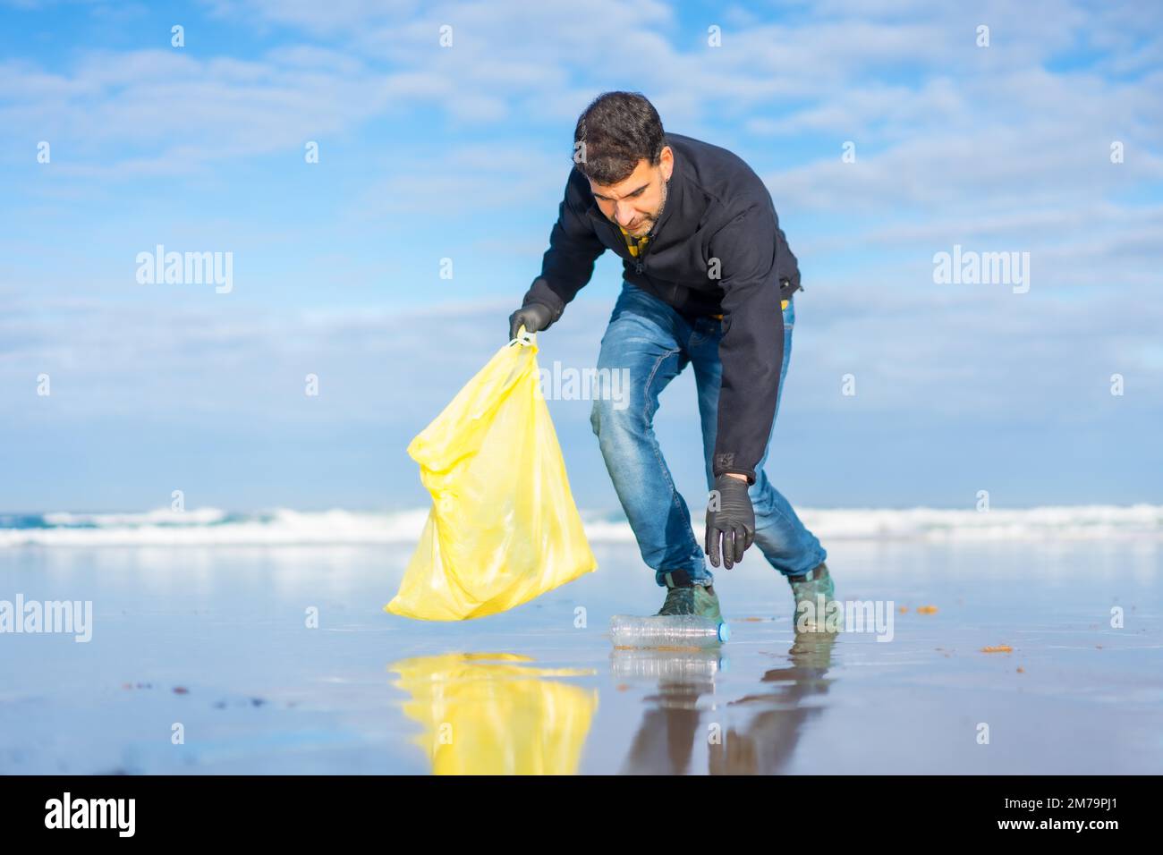 Volunteer man collecting garbage or plastic on the beach. Ecology ...