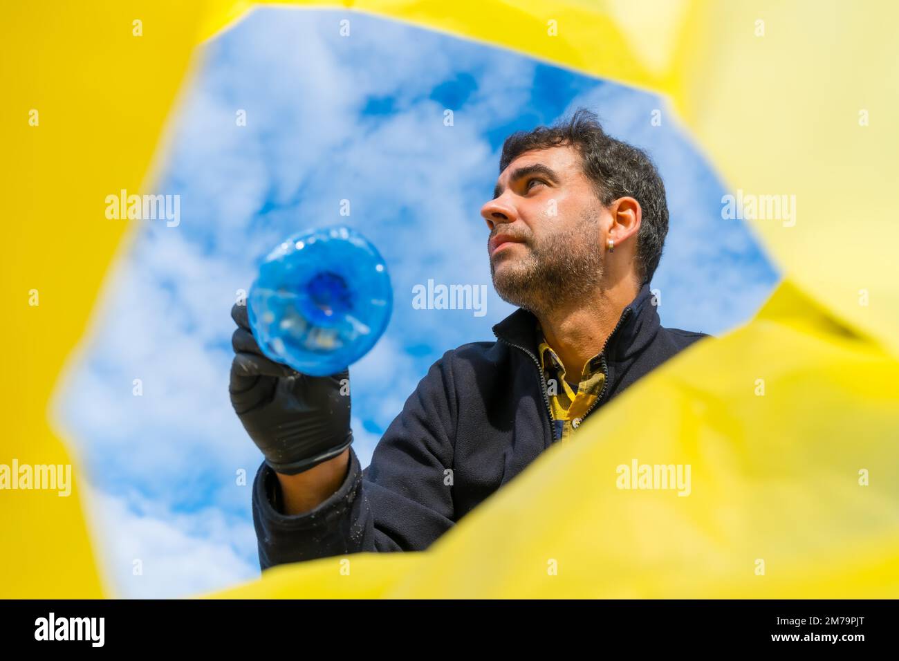 Man throwing a bottle into a garbage bag on the beach. Ecology, Sea ...