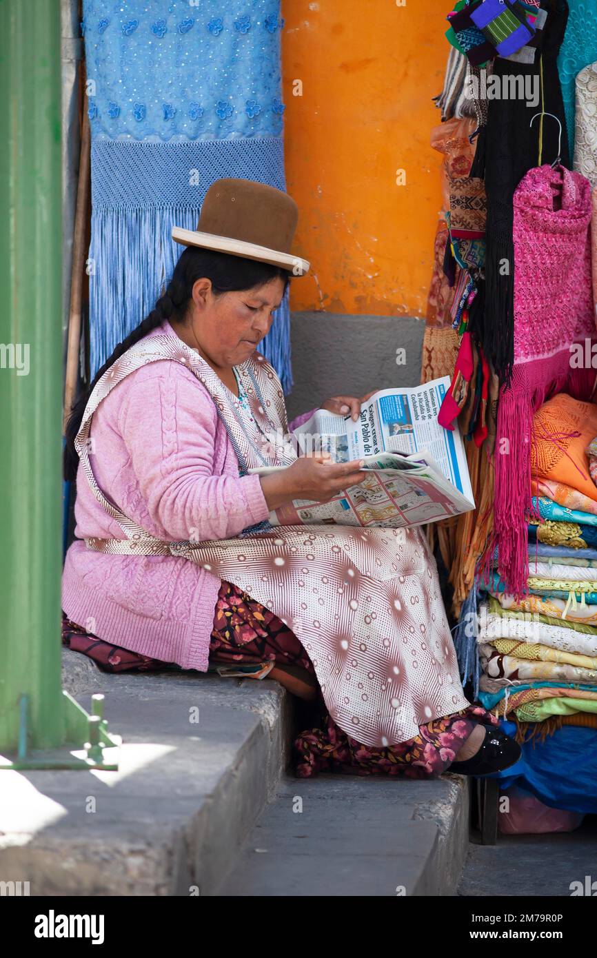Bolivian woman wearing a traditional hat reading a newspaper, La Paz ...