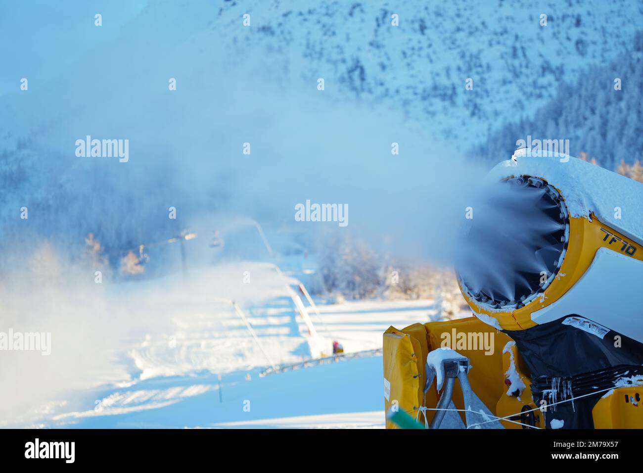 Snow cannon in winter mountains. Snow-gun spraying artificial ice ...