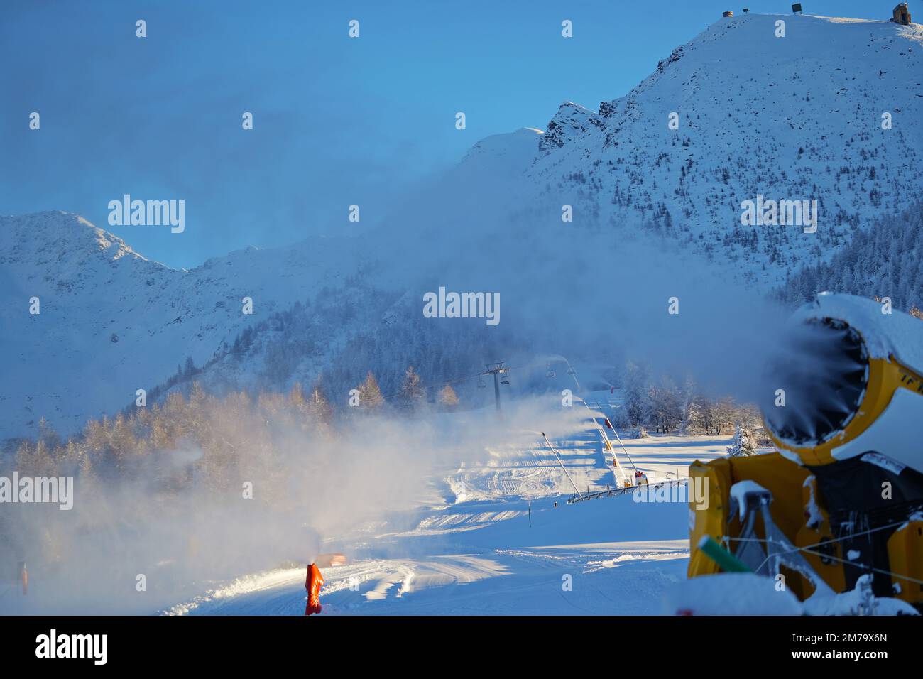 Snow cannon in winter mountains. Snow-gun spraying artificial ice ...
