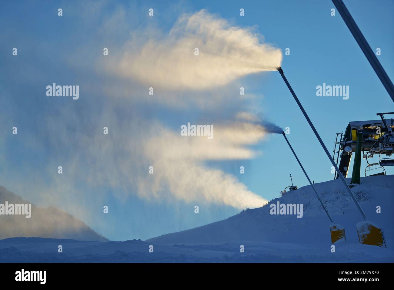 Snow cannon in winter mountains. Snow-gun spraying artificial ice ...