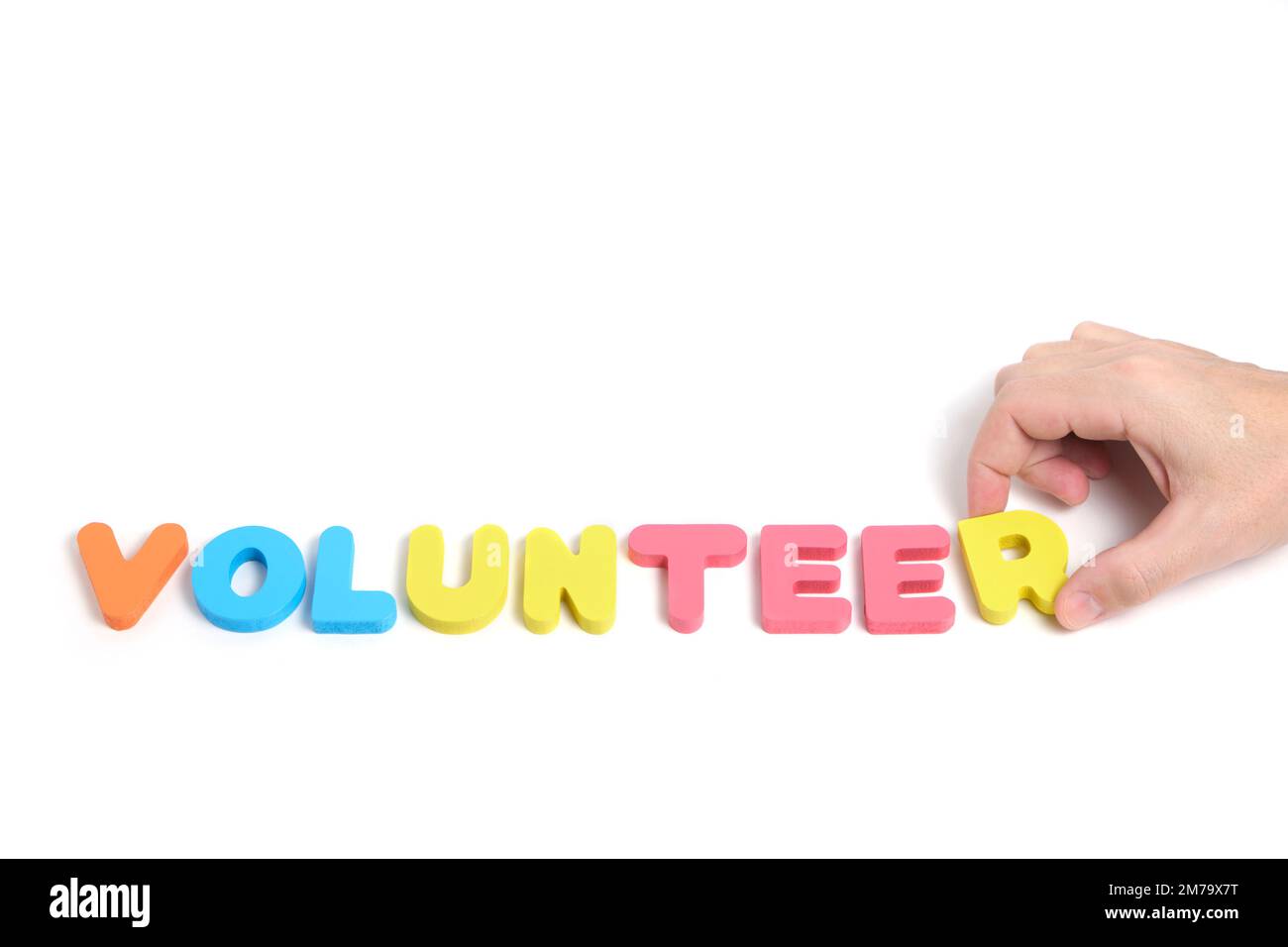 Man hand composes word volunteer from multicolored letters white ...