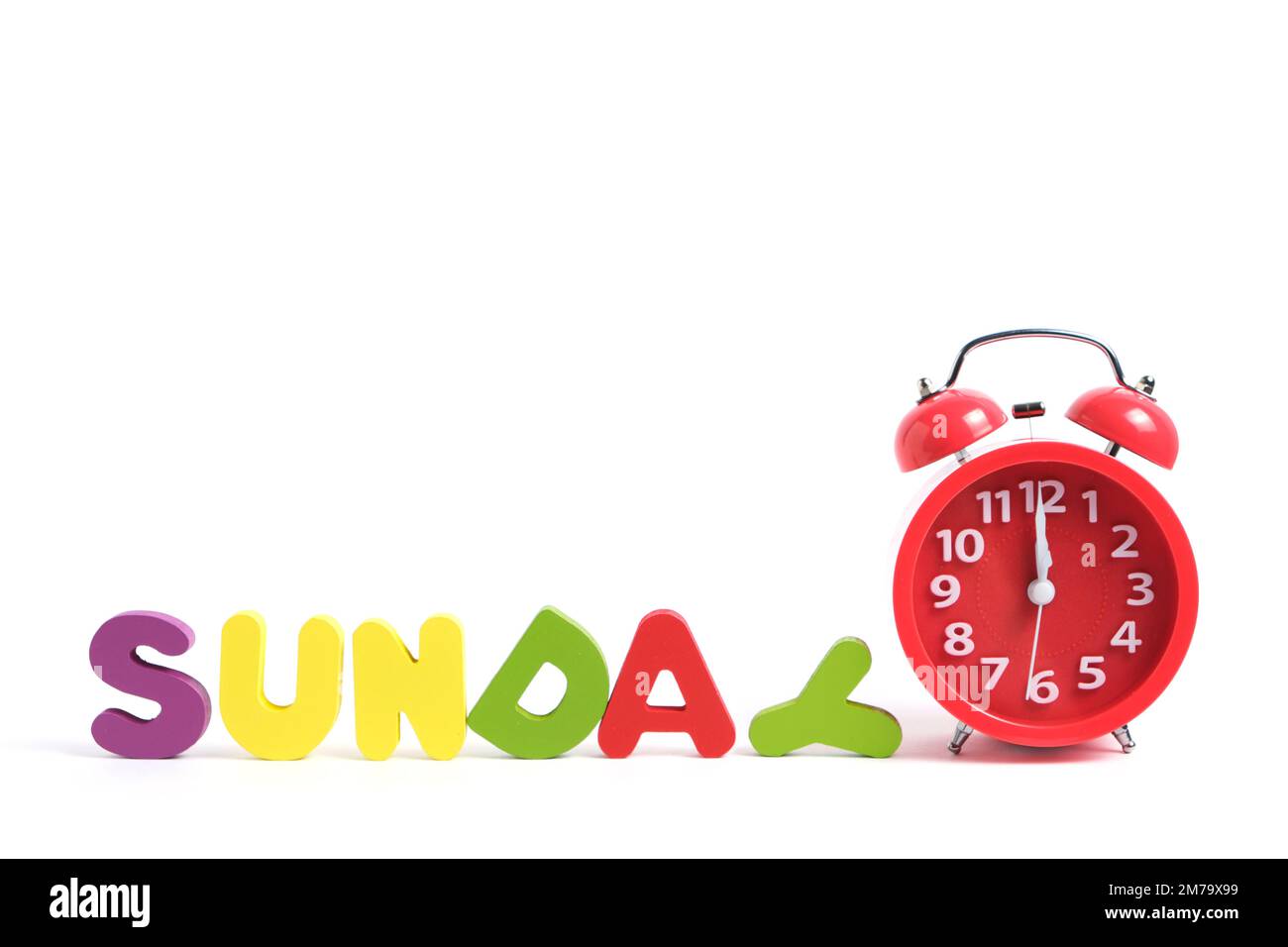 Twelve clock on red alarm clock and word Sunday made up letters white ...