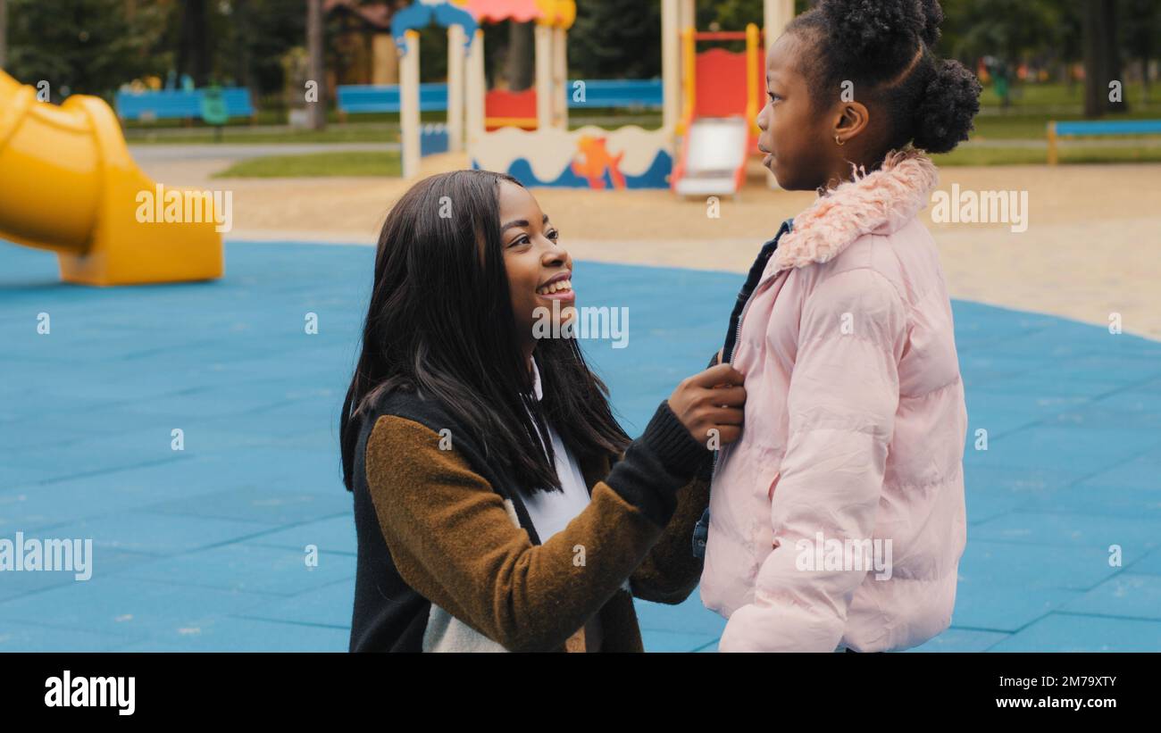Side view mom laugh with daughter in playground cute little girl tell ...