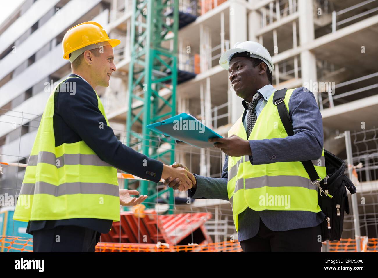 Successful architect and engineer shake hands on construction site ...