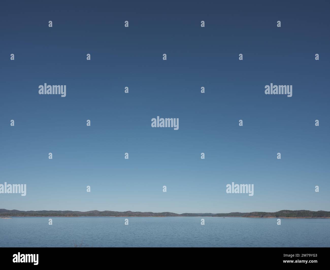 A clear blue sky and still water at the shoreline of a vast lake Stock ...