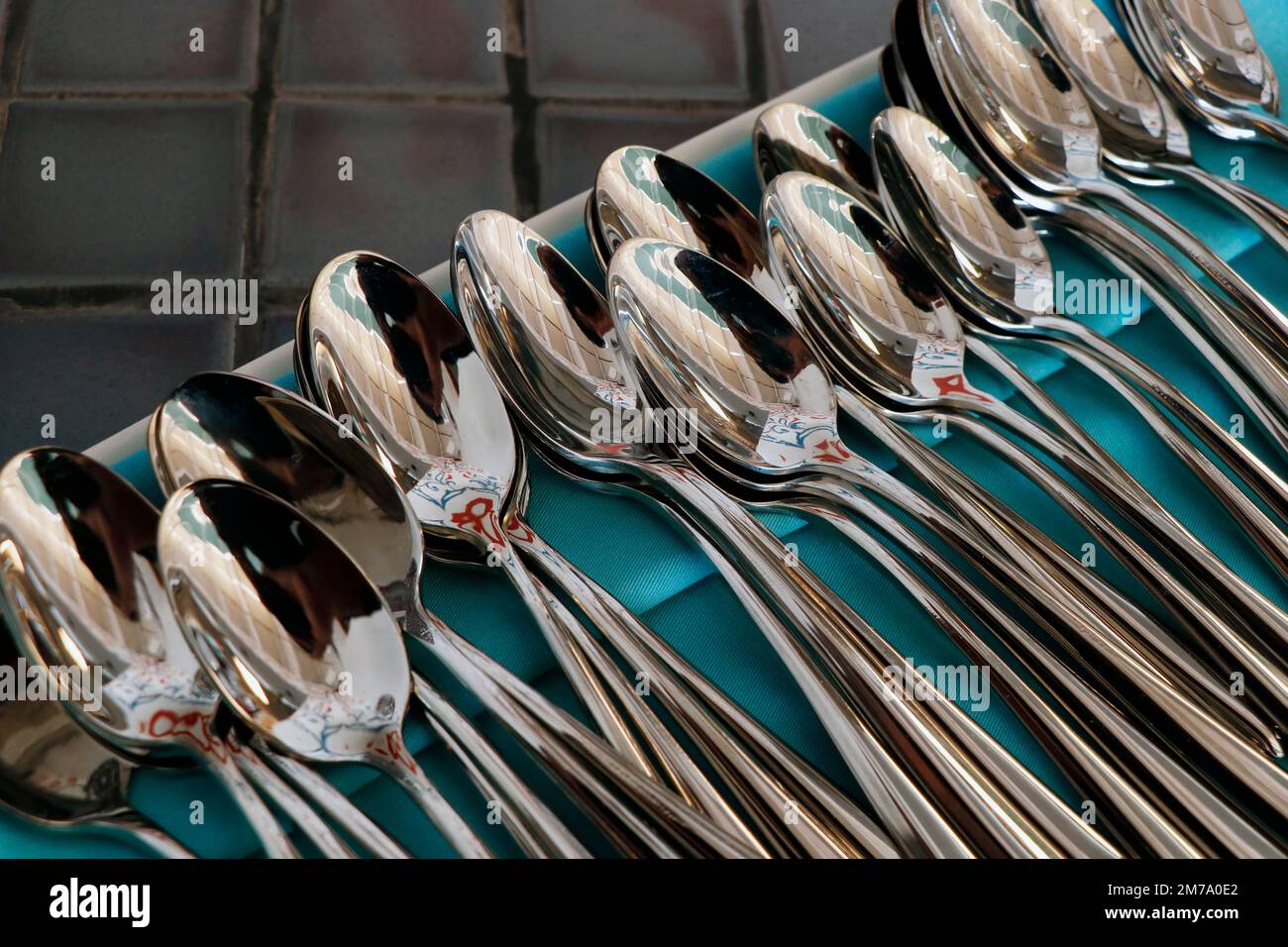 Group of steel metal spoons in tray with green mat, a restaurant side ...