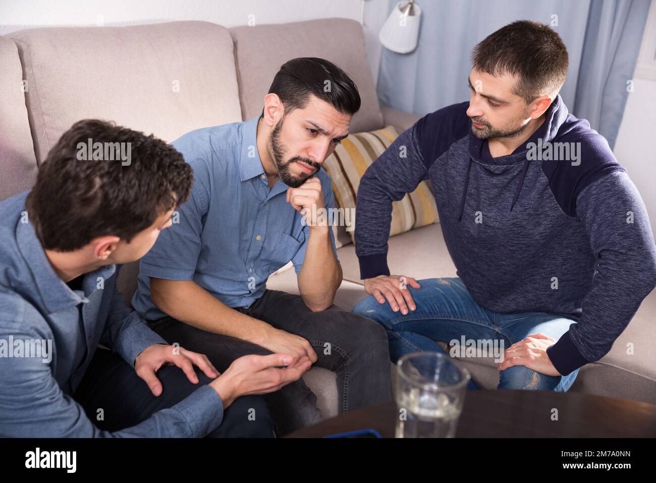 Three anxious men discussing on sofa Stock Photo - Alamy