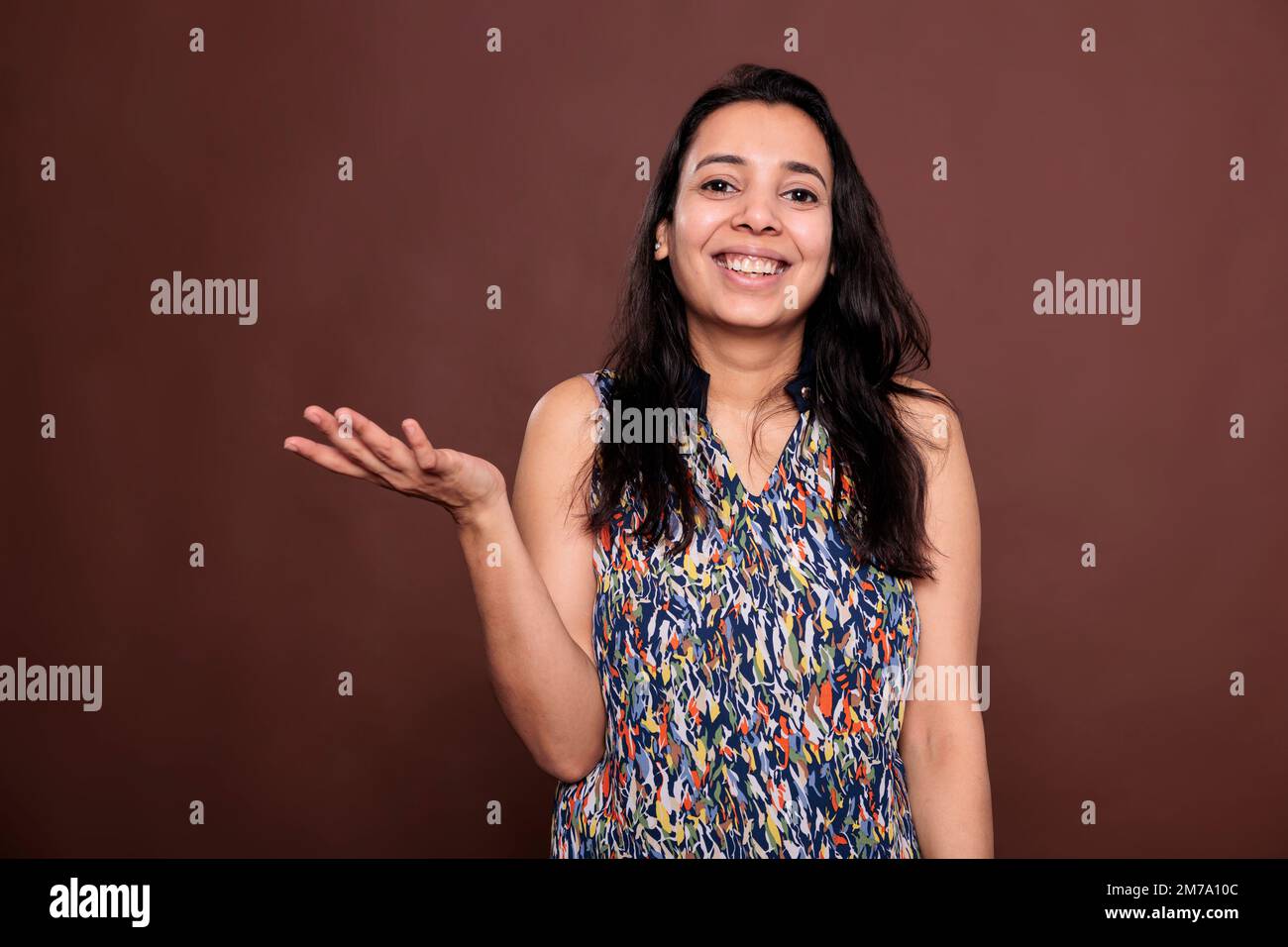 Indian woman smiling, presenting product with raised arm. Cheerful lady ...