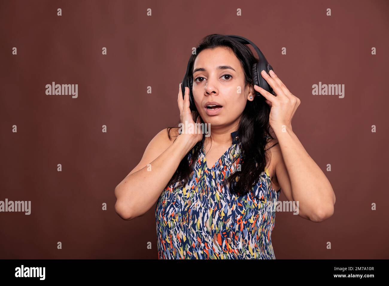 Woman taking off headphones, listening to loud music, looking at camera ...