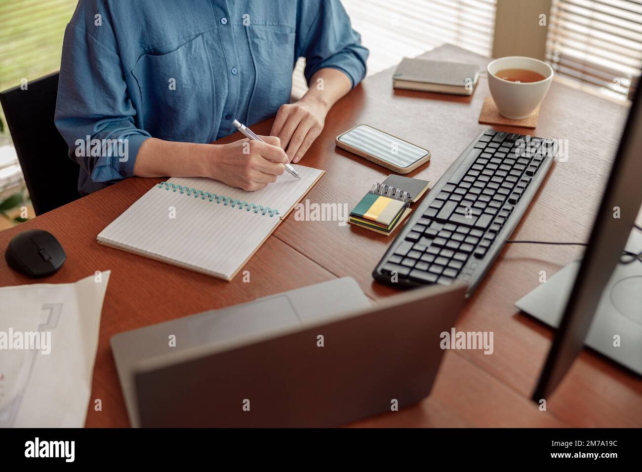 Close up of woman hands taking notes while working in cozy home office ...