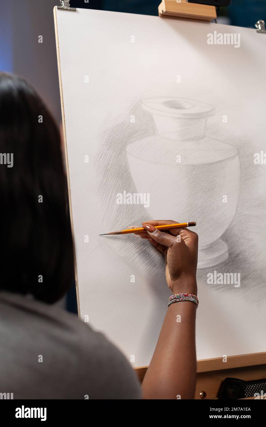 Unrecognizable female artist making pencil drawing on canvas in home ...