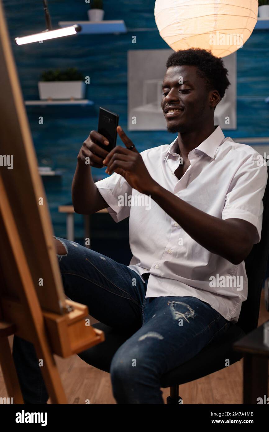 Smiling young man sharing on social media photo of finished artistic ...