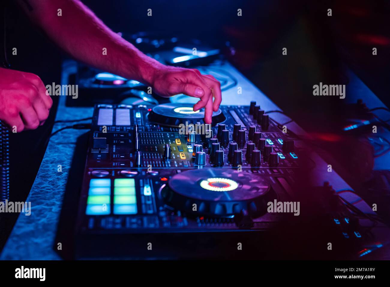 hands of a DJ mixing music on a professional controller in a booth at a ...