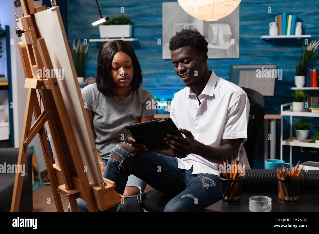Young african american artistic partners watching video tutorials of ...