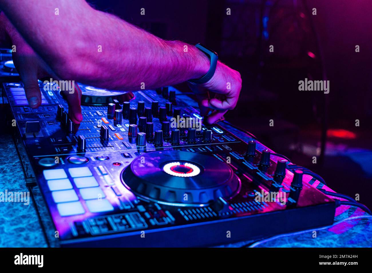 hands of a DJ mixing music on a professional controller in a booth at a ...